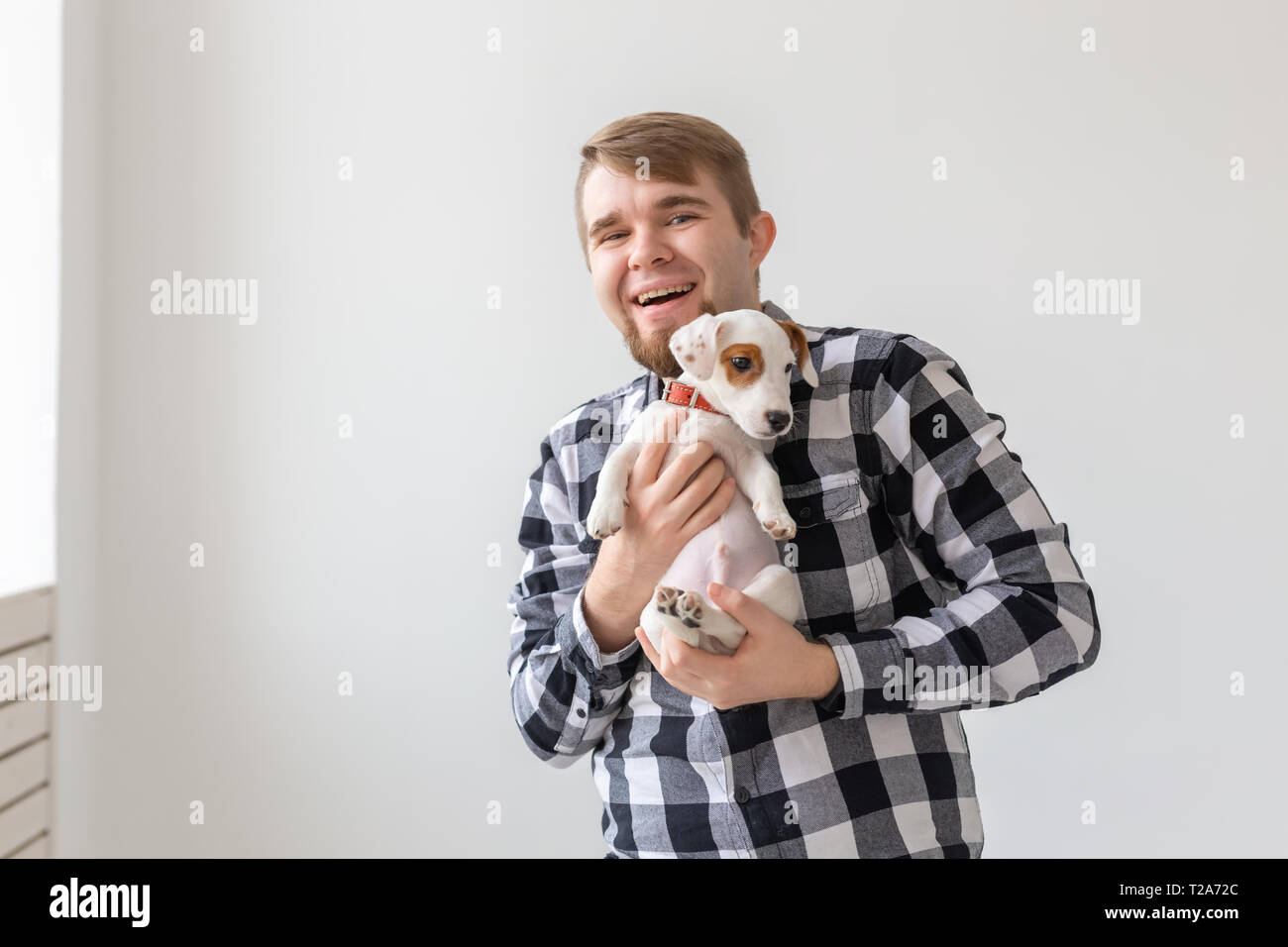 people, pets and dogs concept - young man hugging puppy on white ...