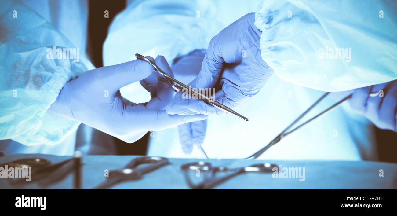Surgeons hands holding surgical scissors and passing surgical equipment ...