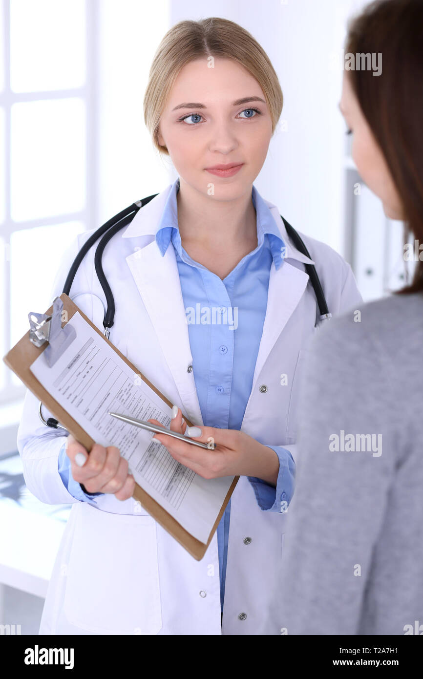 Young woman doctor and patient looking at medication history records ...