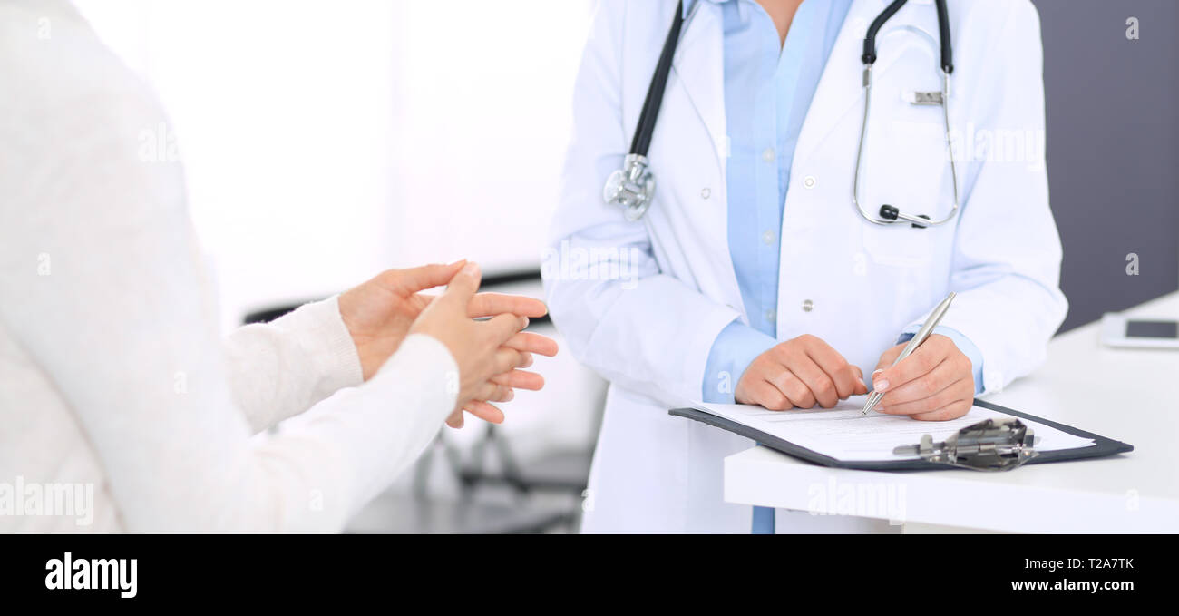 Unknown woman doctor and female patient discussing something while ...
