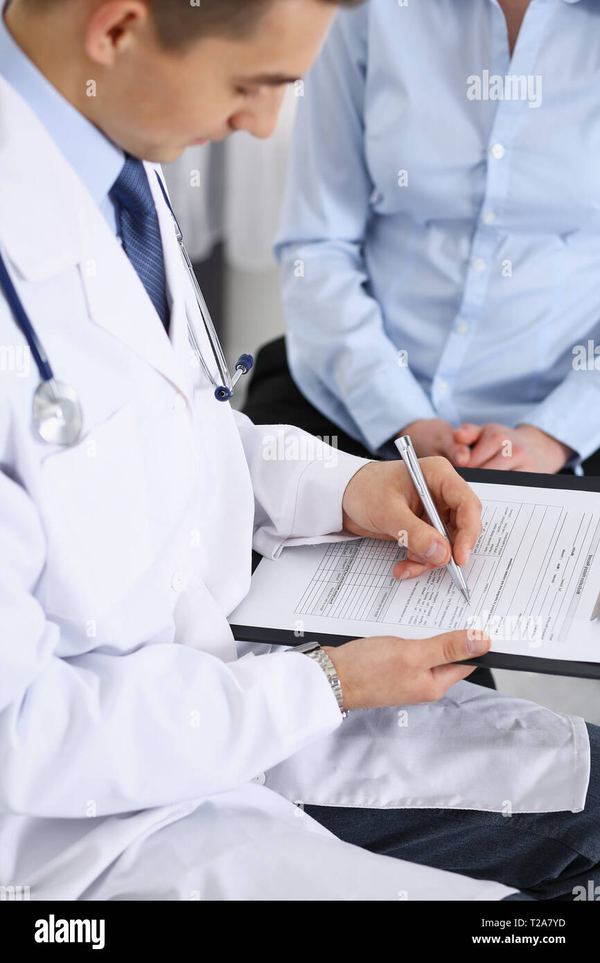 Male doctor holding application form while consulting female patient in ...