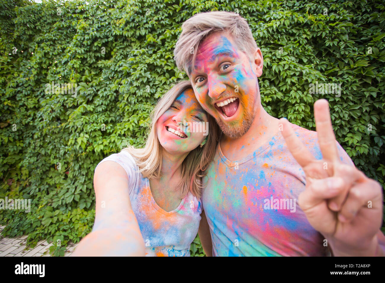Holiday and people concept - Woman and man with painted faces taking ...