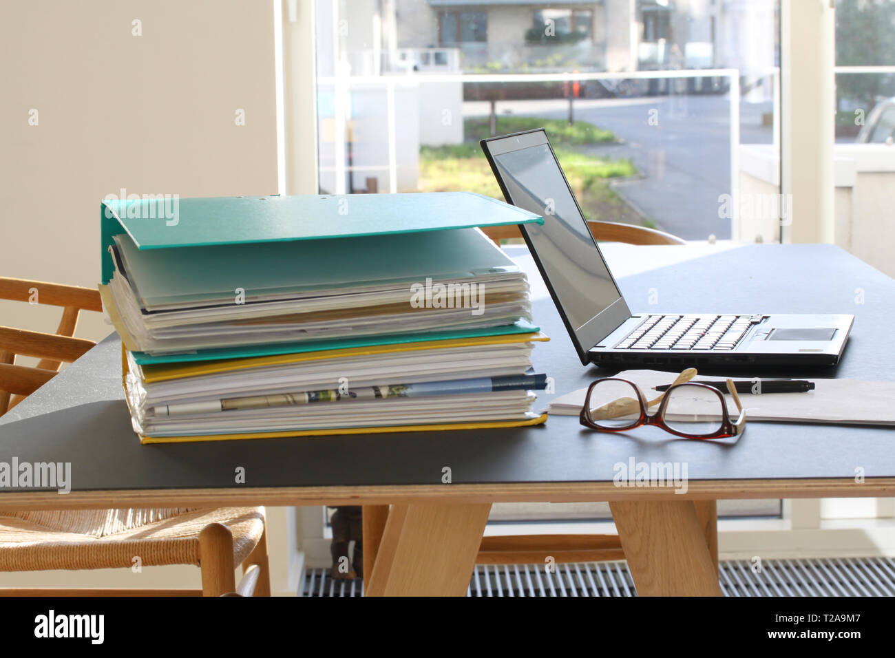 Laptop computer, ring binders filled with papers, glasses, paper sheets ...