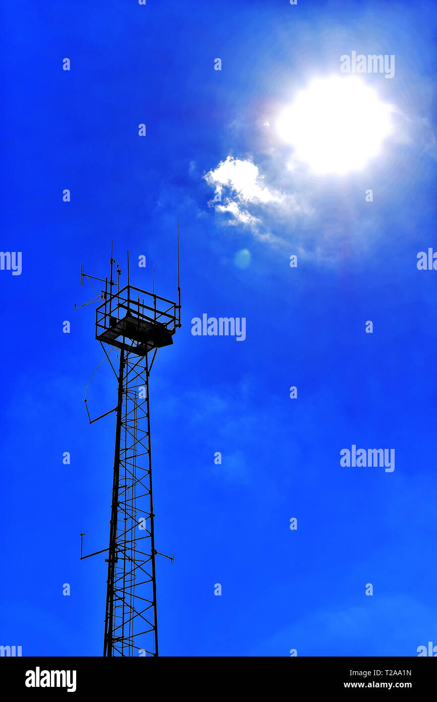Comms tower in sunlight against blue sky Stock Photo - Alamy