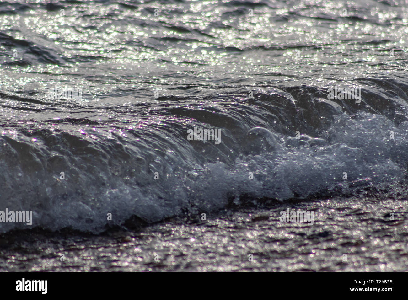 Small ocean waves breaking on a stoney beach Stock Photo - Alamy