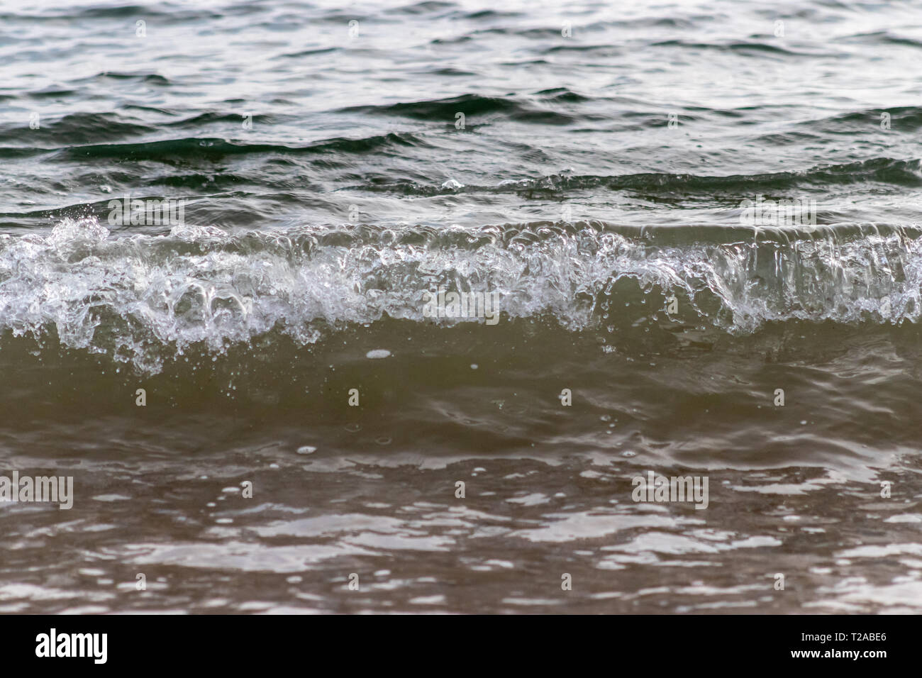 Small ocean waves breaking on a stoney beach Stock Photo - Alamy