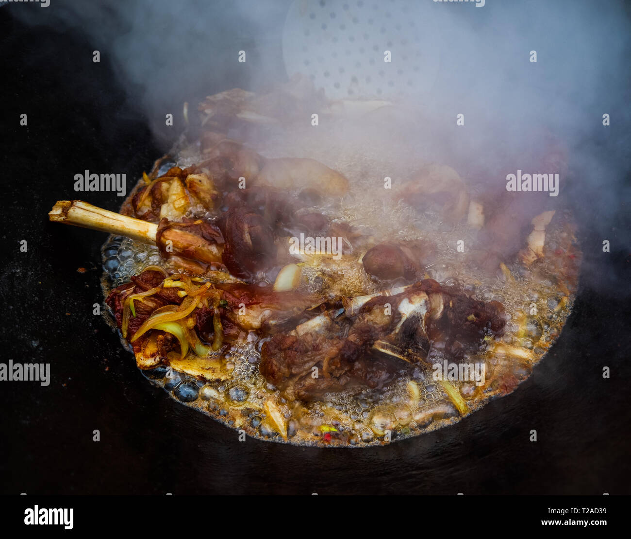 Lamb in a large cast-iron cauldron on fire. Pilaf cooking process Stock ...