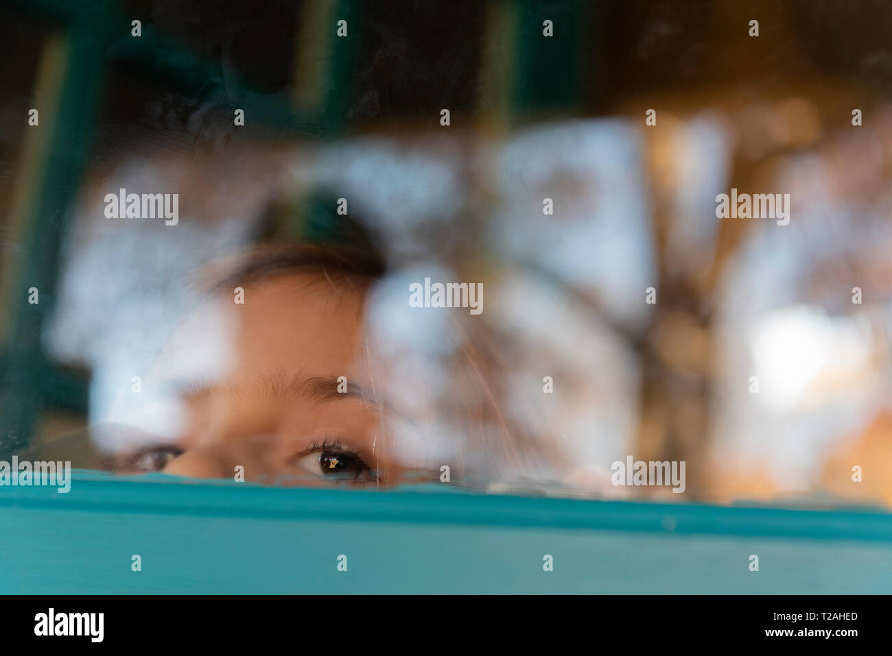 Girl peering through window Stock Photo - Alamy