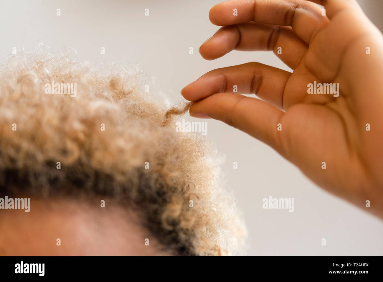 Hand of woman holding curly hair Stock Photo - Alamy