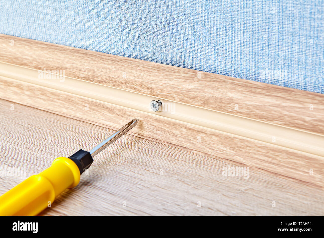Tightening screw in cable channel of floor plinth by screwdriver Stock ...