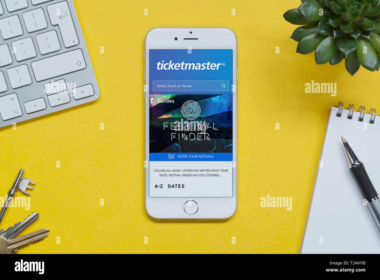 An iPhone showing the Ticketmaster website rests on a yellow background ...