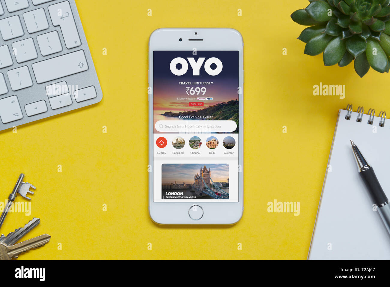 An iPhone showing the Oyo Rooms website rests on a yellow background ...