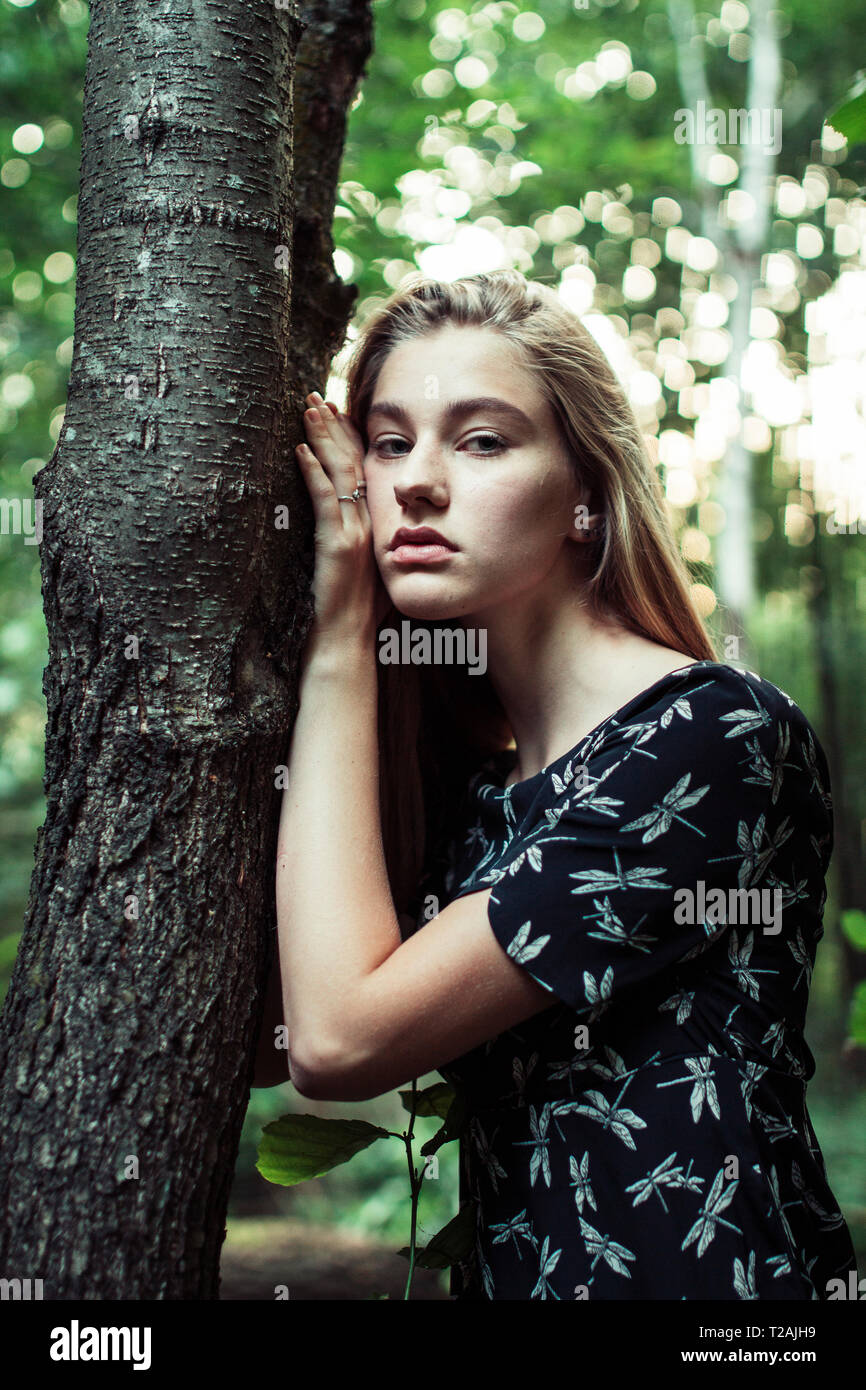 Young woman leaning on tree trunk hi-res stock photography and images ...