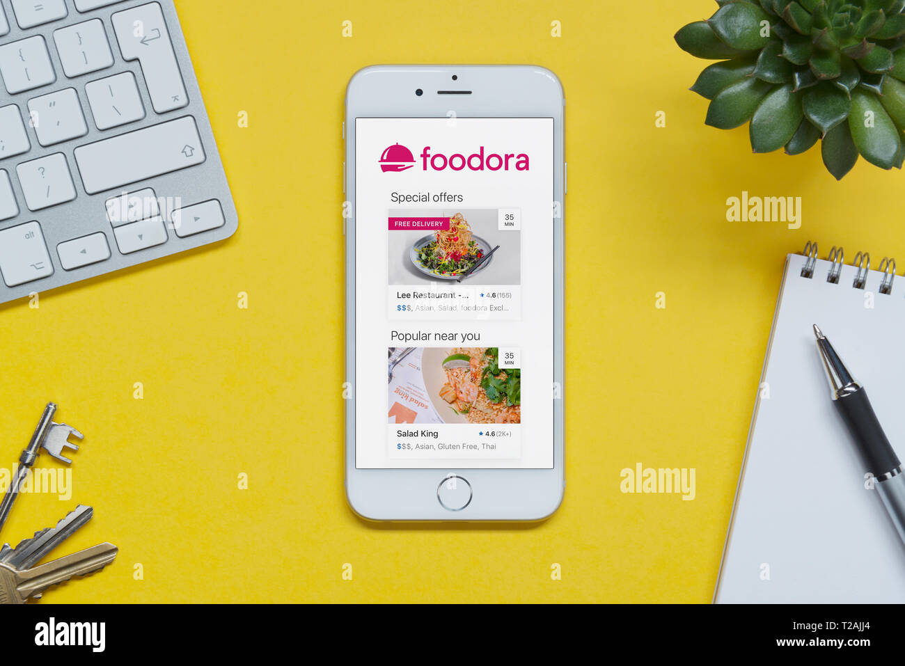 An iPhone showing the Foodora website rests on a yellow background ...