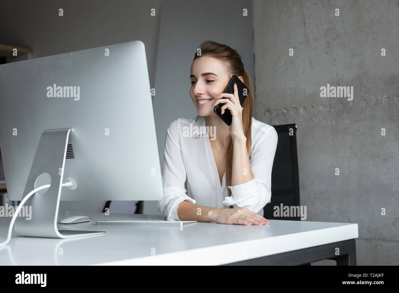 Smiling businesswoman taking phone call at desk Stock Photo - Alamy