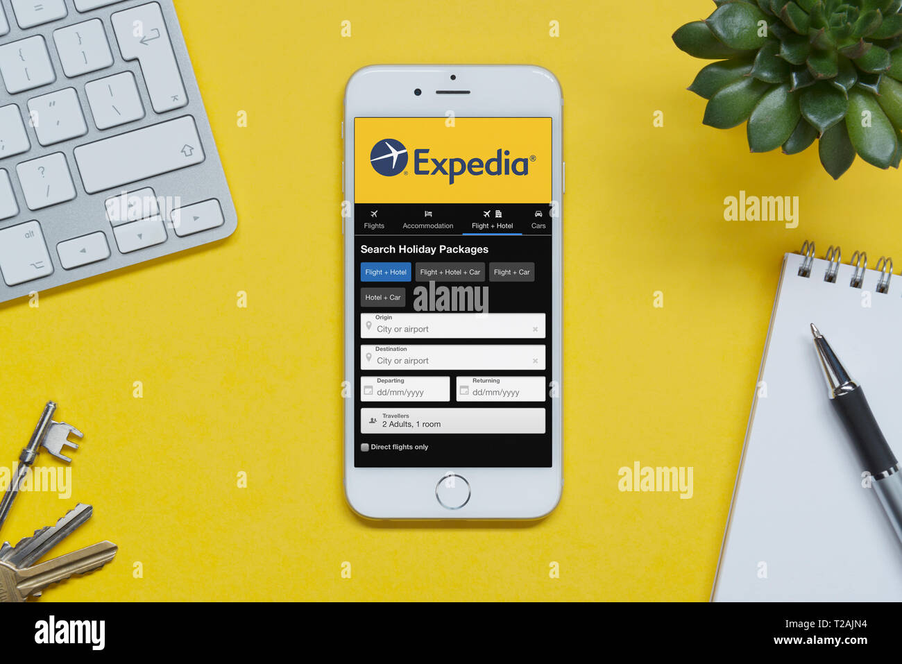 An iPhone showing the Expedia website rests on a yellow background ...