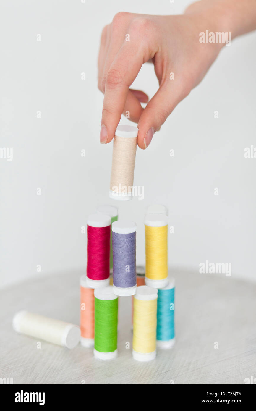 Hand of woman stacking colorful spools of thread Stock Photo - Alamy