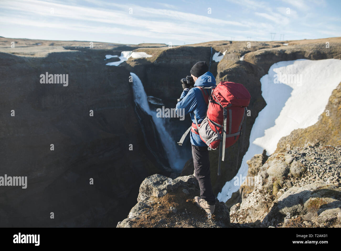Hiker with backpack on cliff by Haifoss waterfall in Iceland Stock ...
