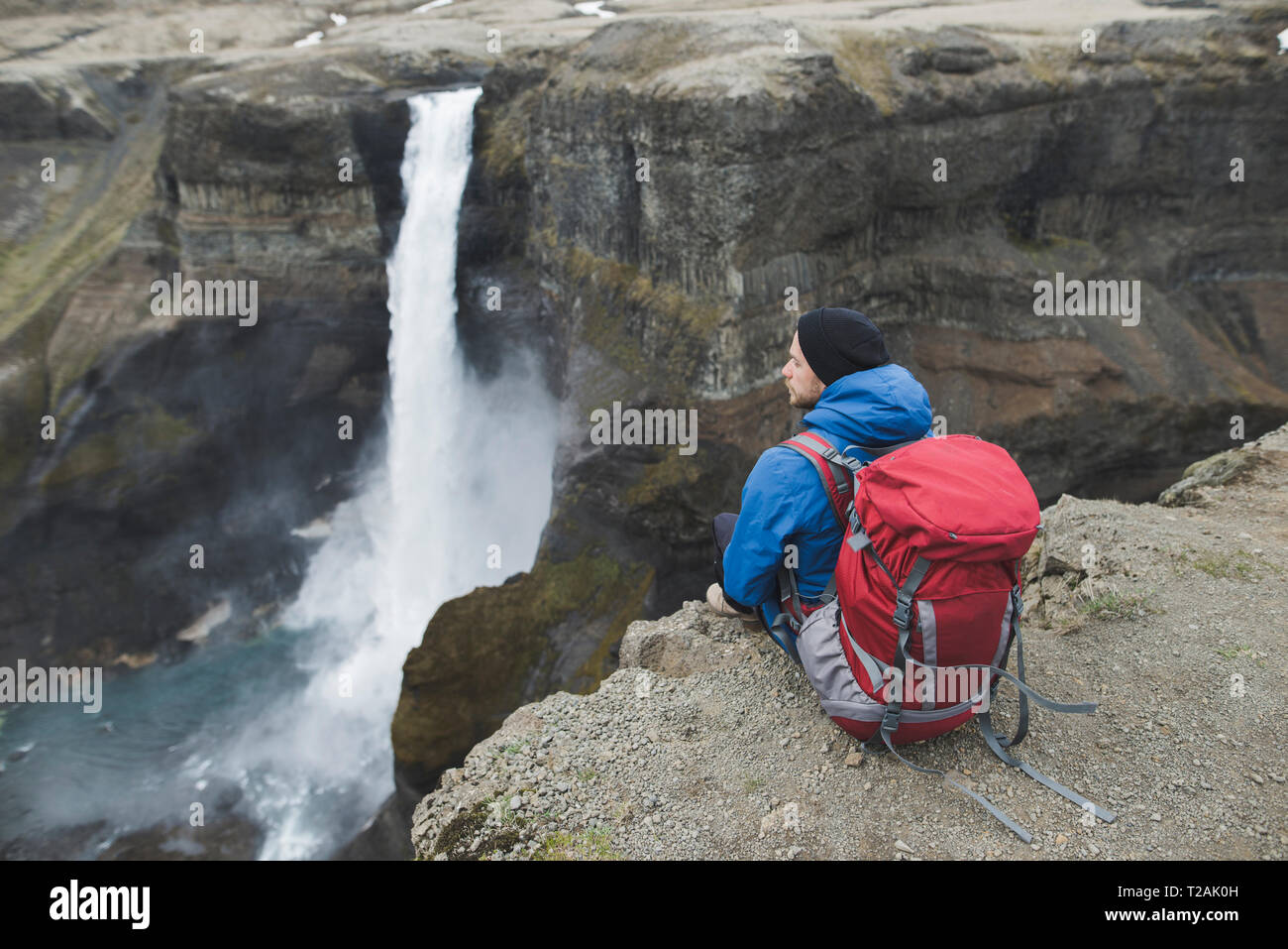 Hiker with backpack on cliff by Haifoss waterfall in Iceland Stock ...