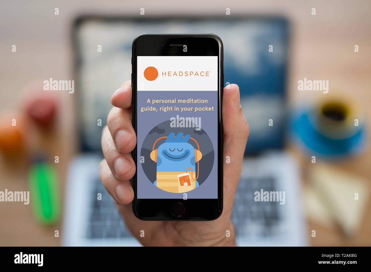 A man looks at his iPhone which displays the Headspace logo (Editorial ...