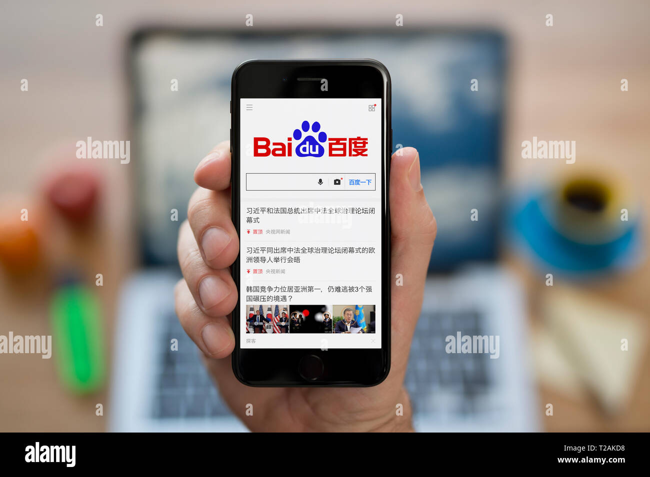 A man looks at his iPhone which displays the Baidu logo (Editorial use ...