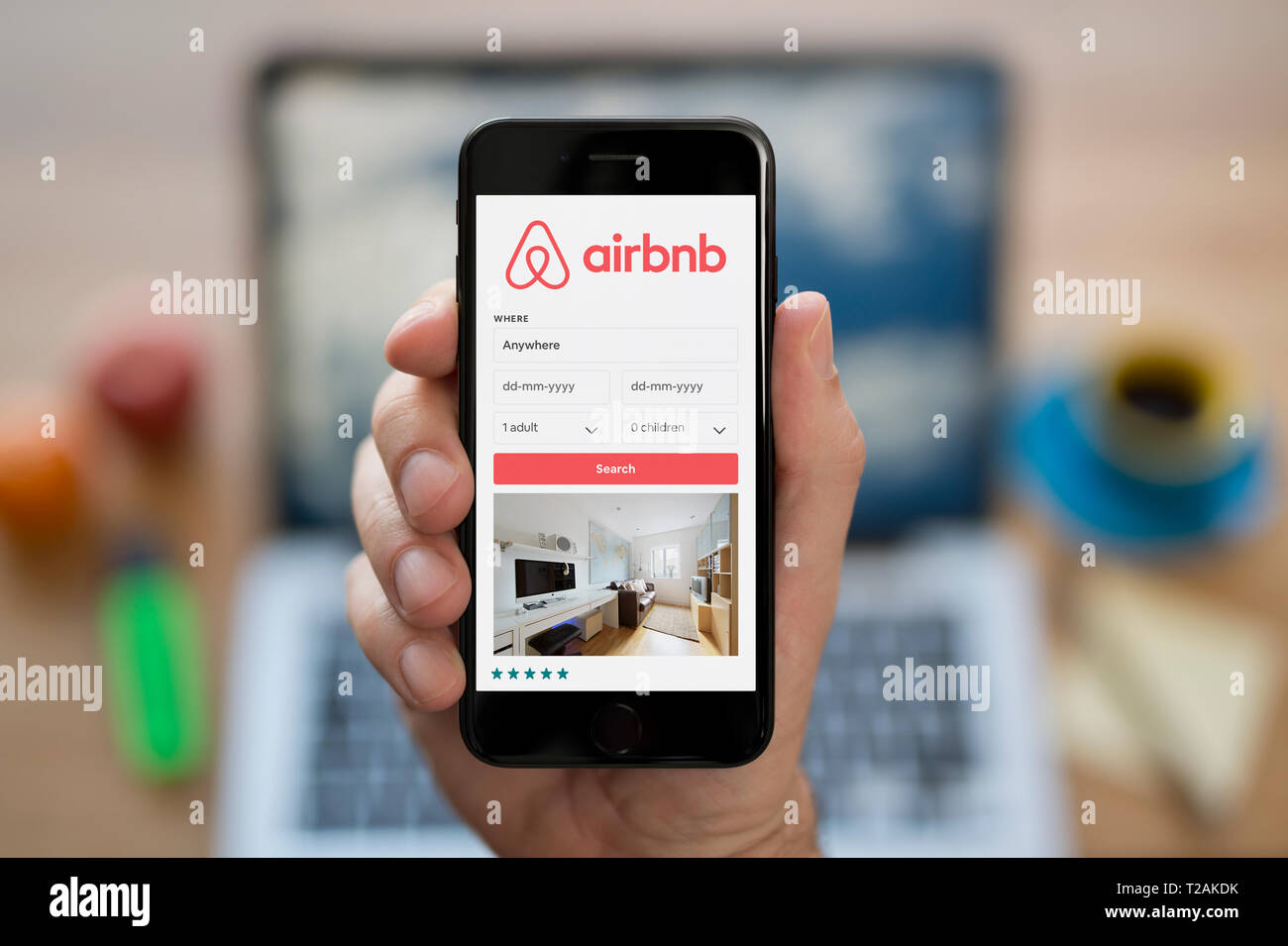 A man looks at his iPhone which displays the Airbnb logo (Editorial use ...