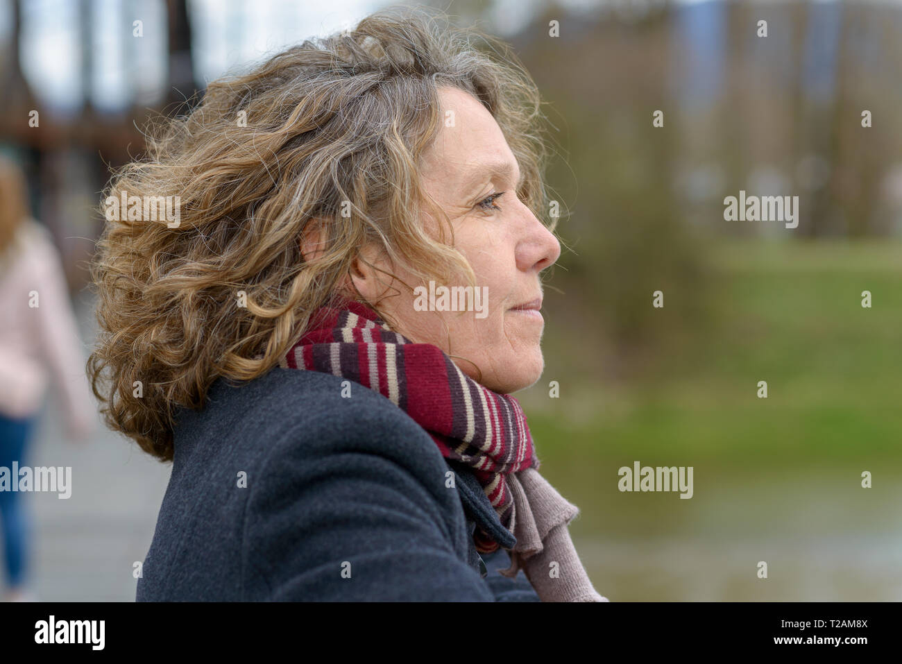 attractive middle-aged woman deep in thought leaning on the railing of ...