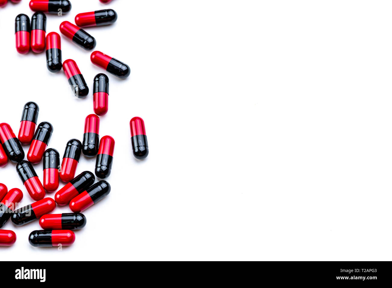 Red-black capsule pills spread on white background. Antibiotic drug use ...