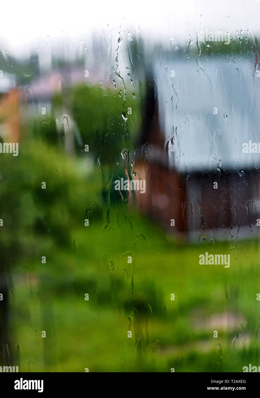 view of the wooden house from the wet window on a rainy day, blur ...