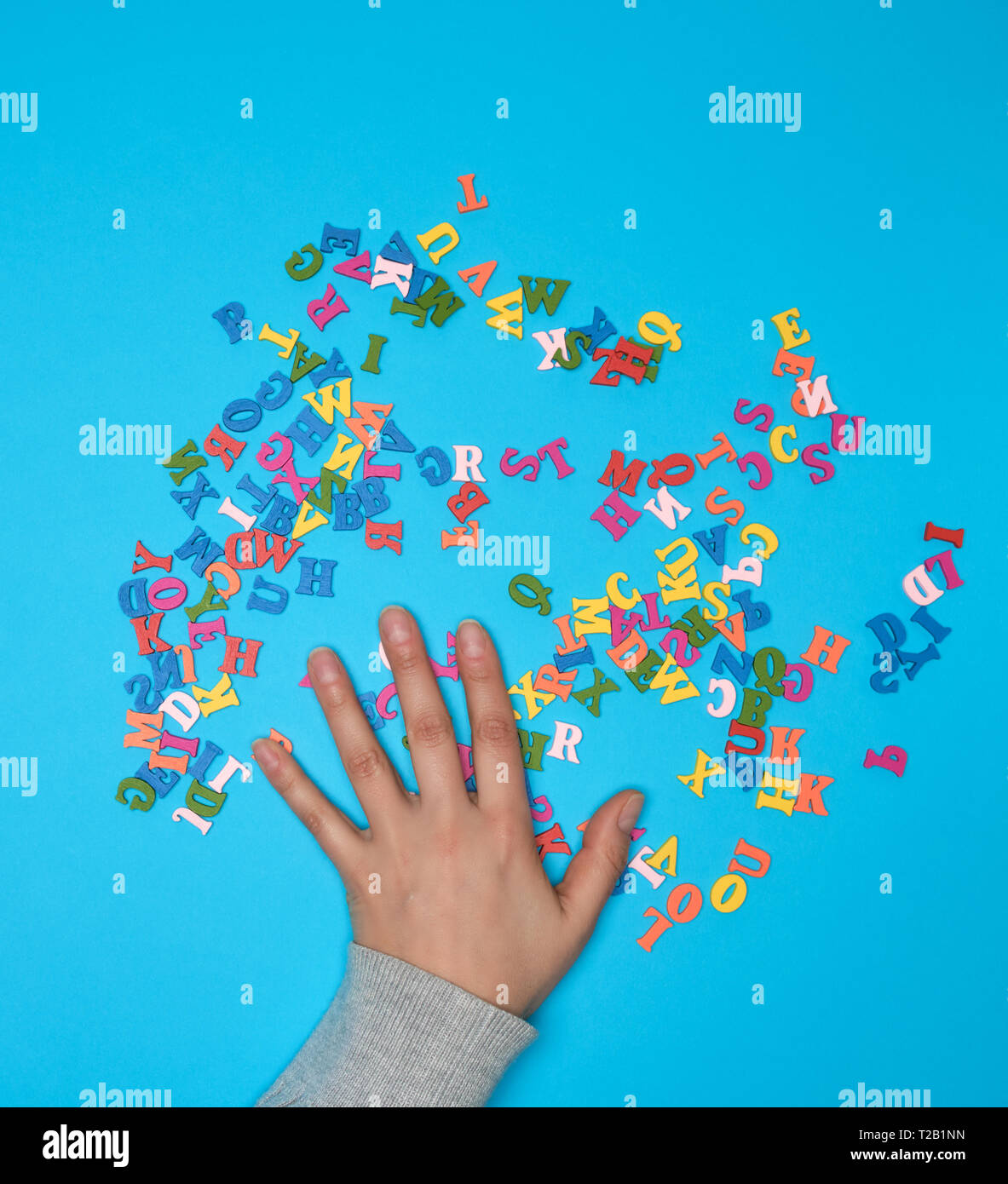 female hand and multicolored wooden letters of the English alphabet on ...