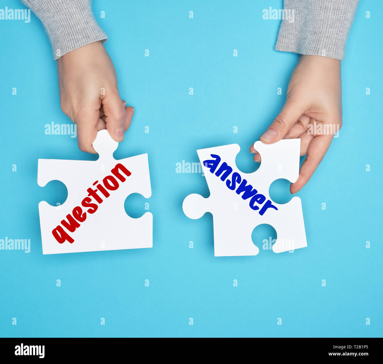 Two female hands holding big paper white puzzles with a question and ...