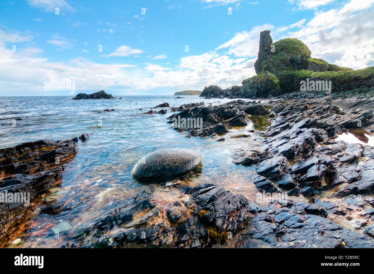 Jagged rock layers and boulders smoothed by the ocean are seen at an ...