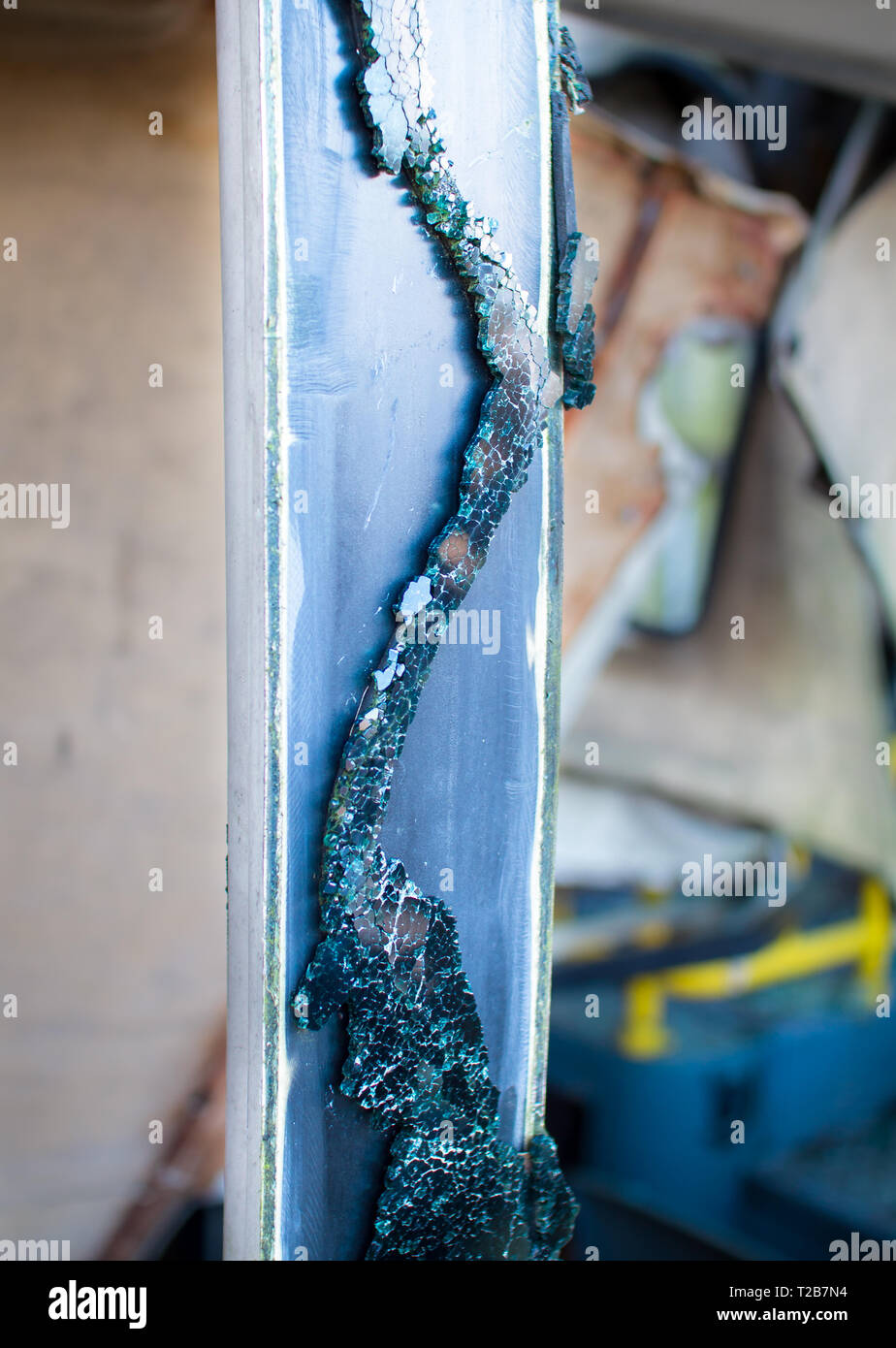 Broken glass remains stuck to a metal pole on a wrecked minibus at the ...