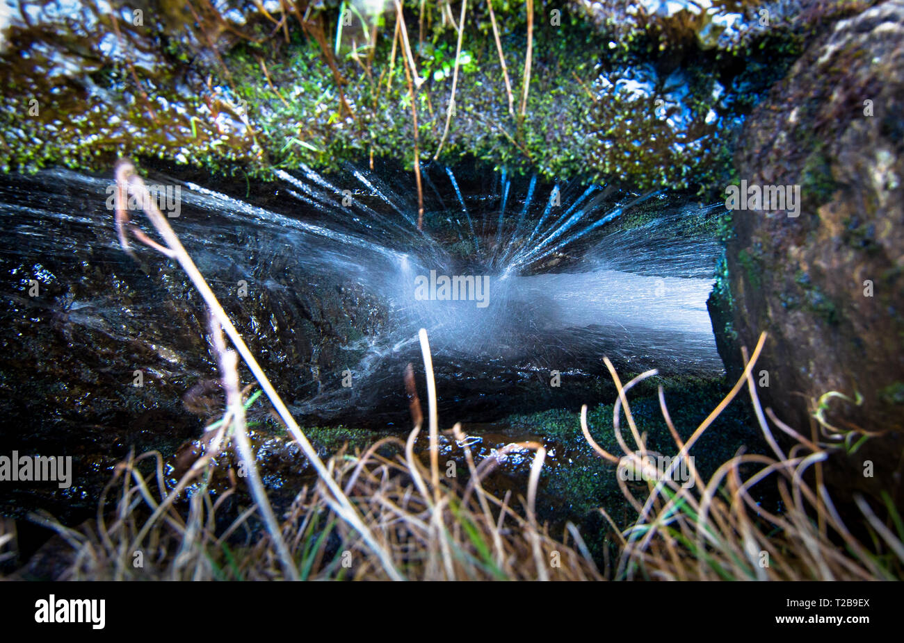 Water falls into a deep narrow hole in the rock in the Peak District ...