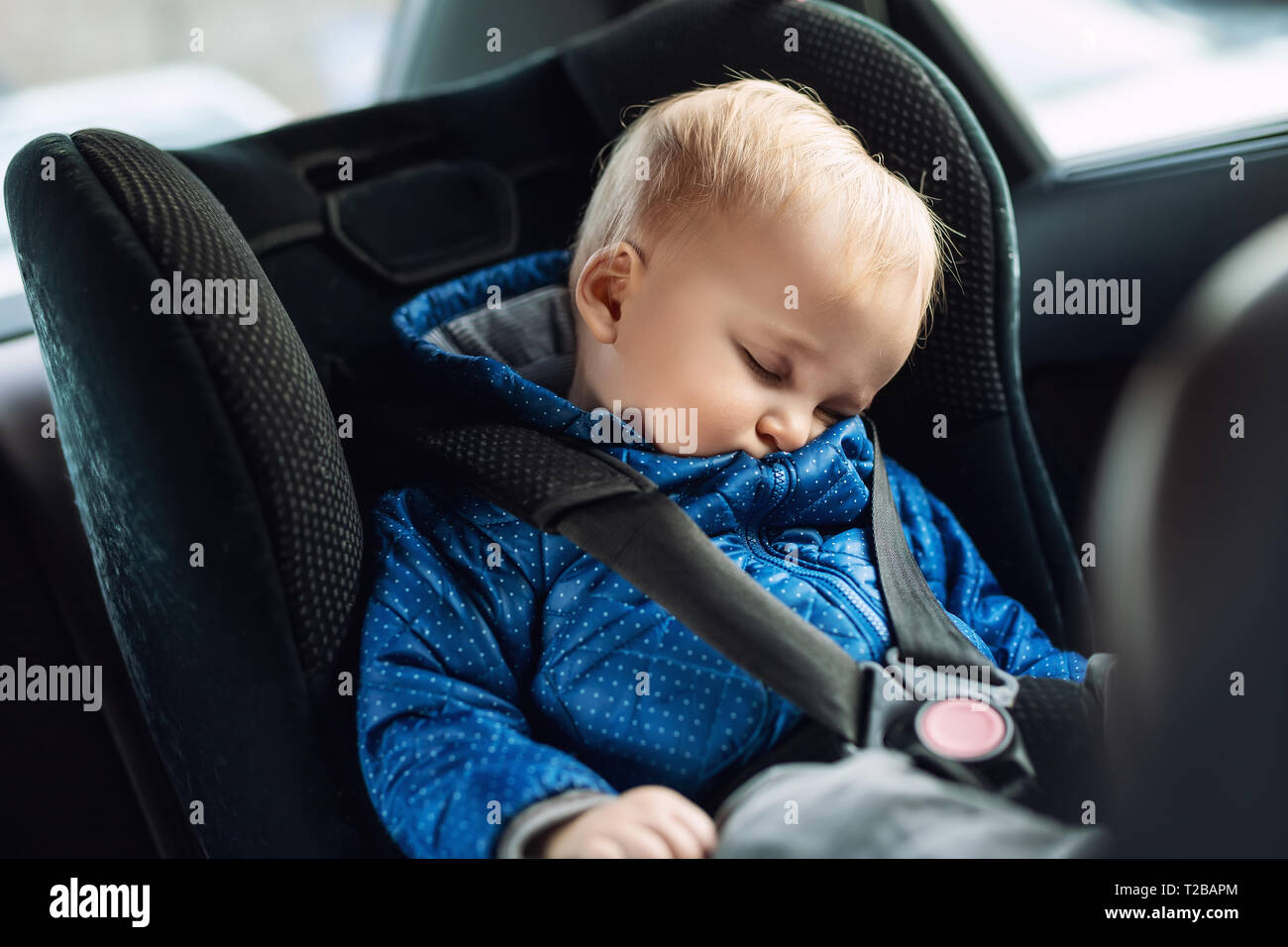 Cute caucasian toodler boy sleeping in child safety seat in car during ...