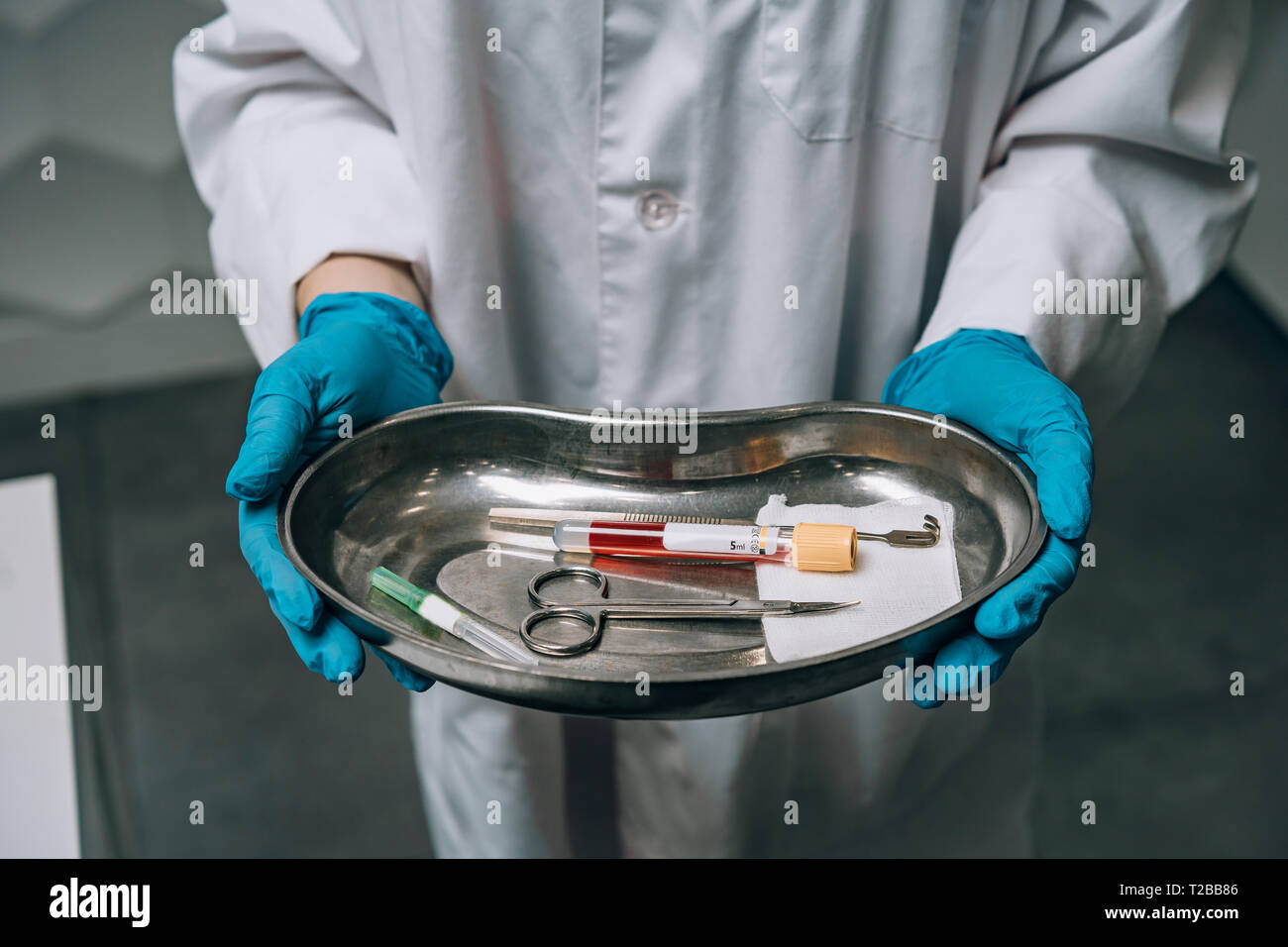 Nurse in rubber gloves holding a tray of surgical medical equipment ...