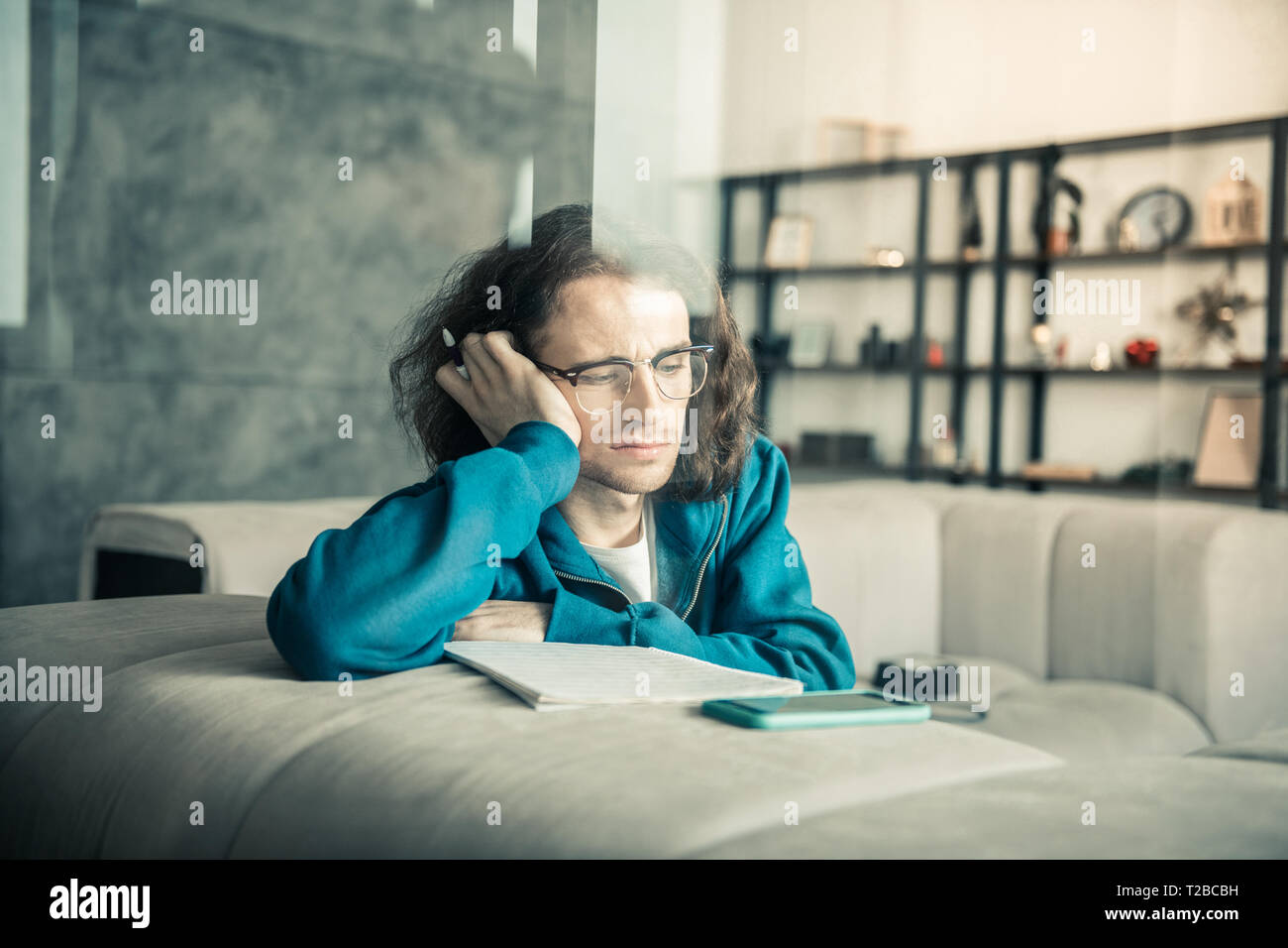 Confused dark-haired young musician being stuck during creating process ...