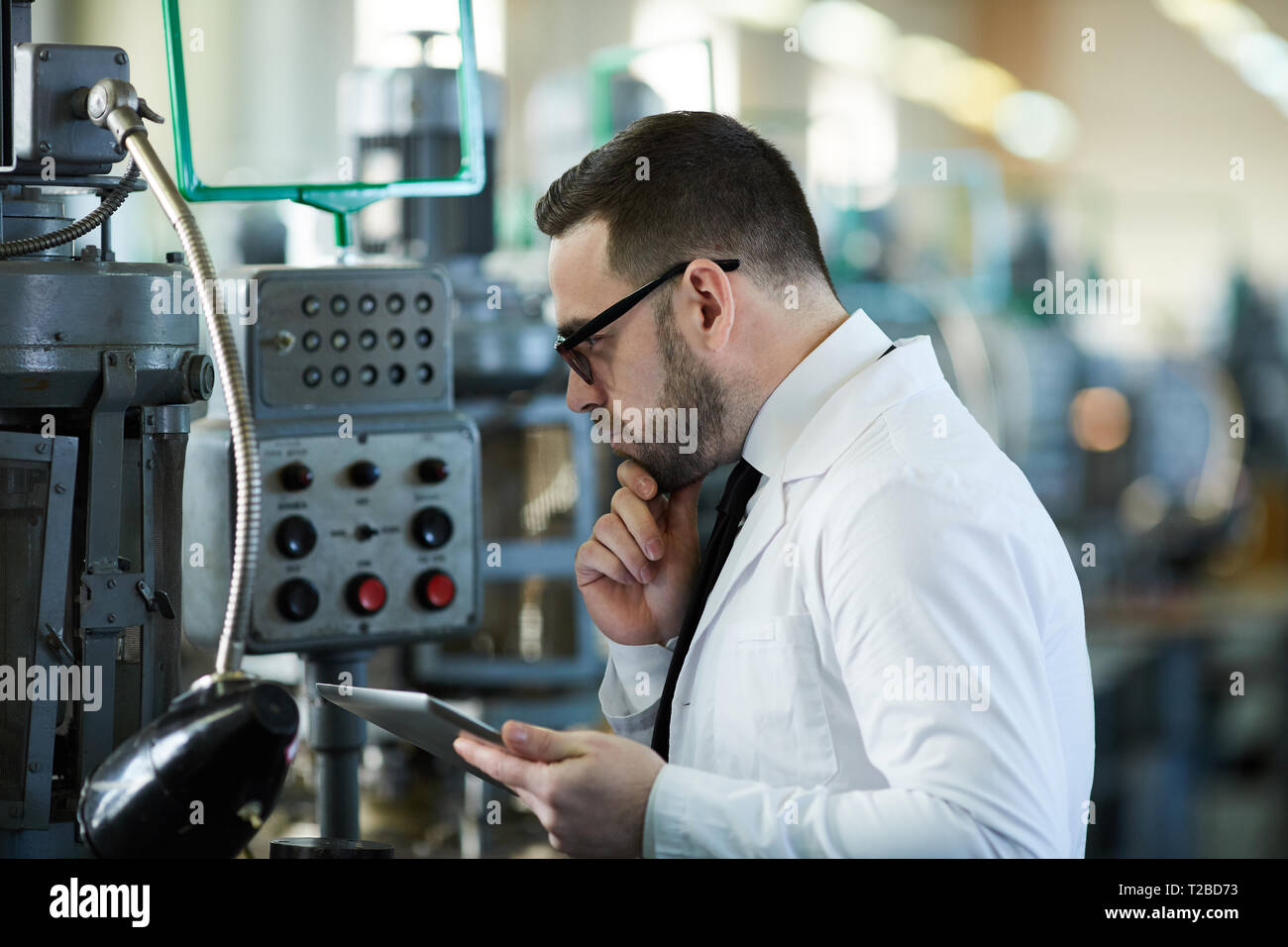 Side view portrait of bearded factory worker operating machine units in ...
