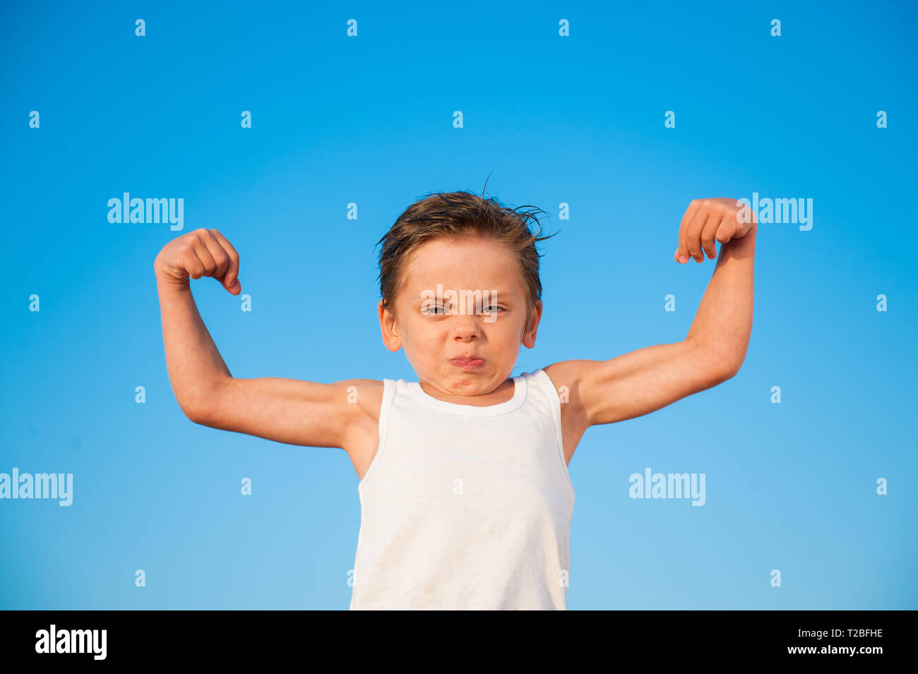 cute aggressive little kid in white tank top showing muscle biceps on ...