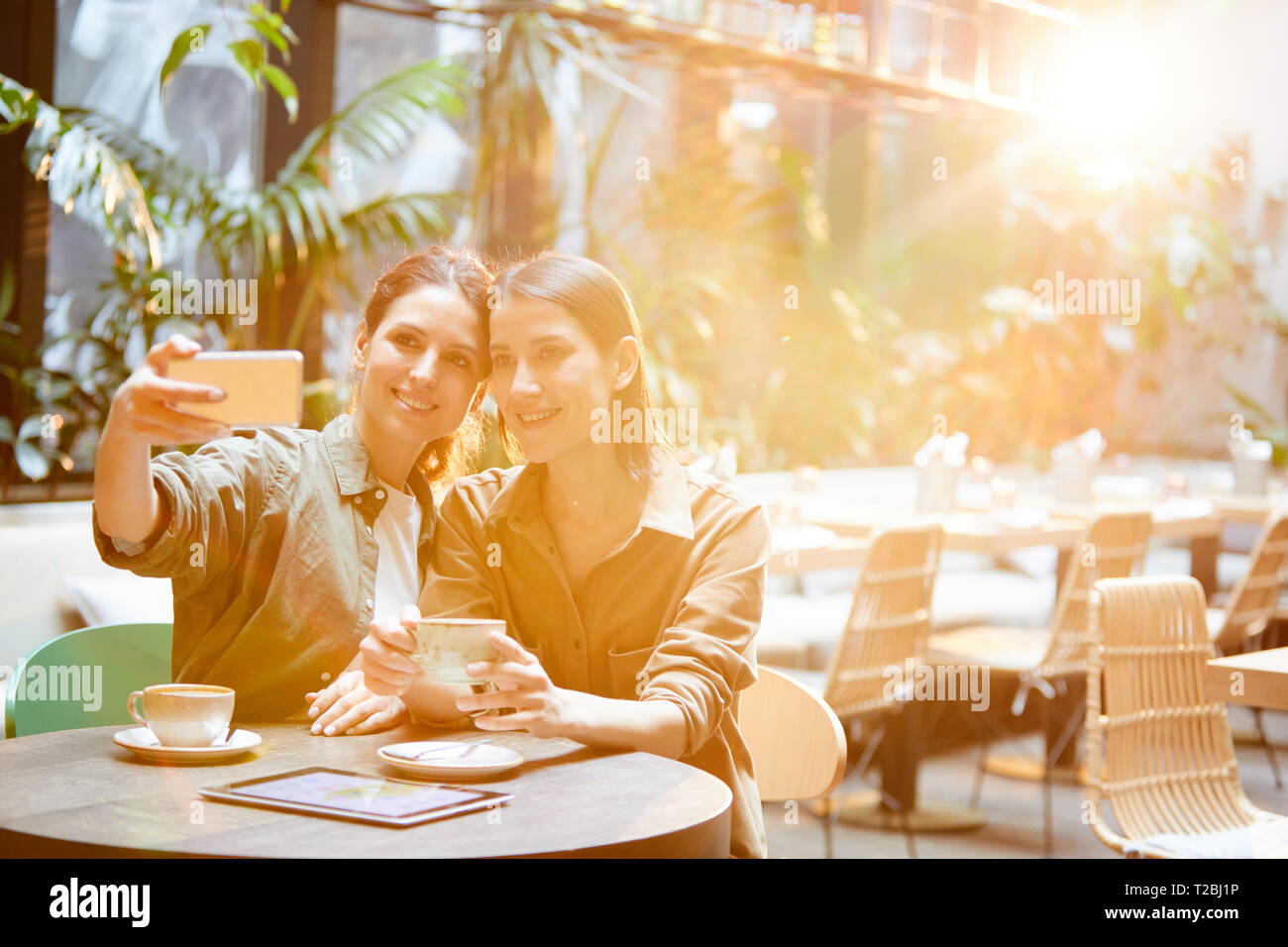 Pretty women talking selfie in tropical cafe Stock Photo - Alamy
