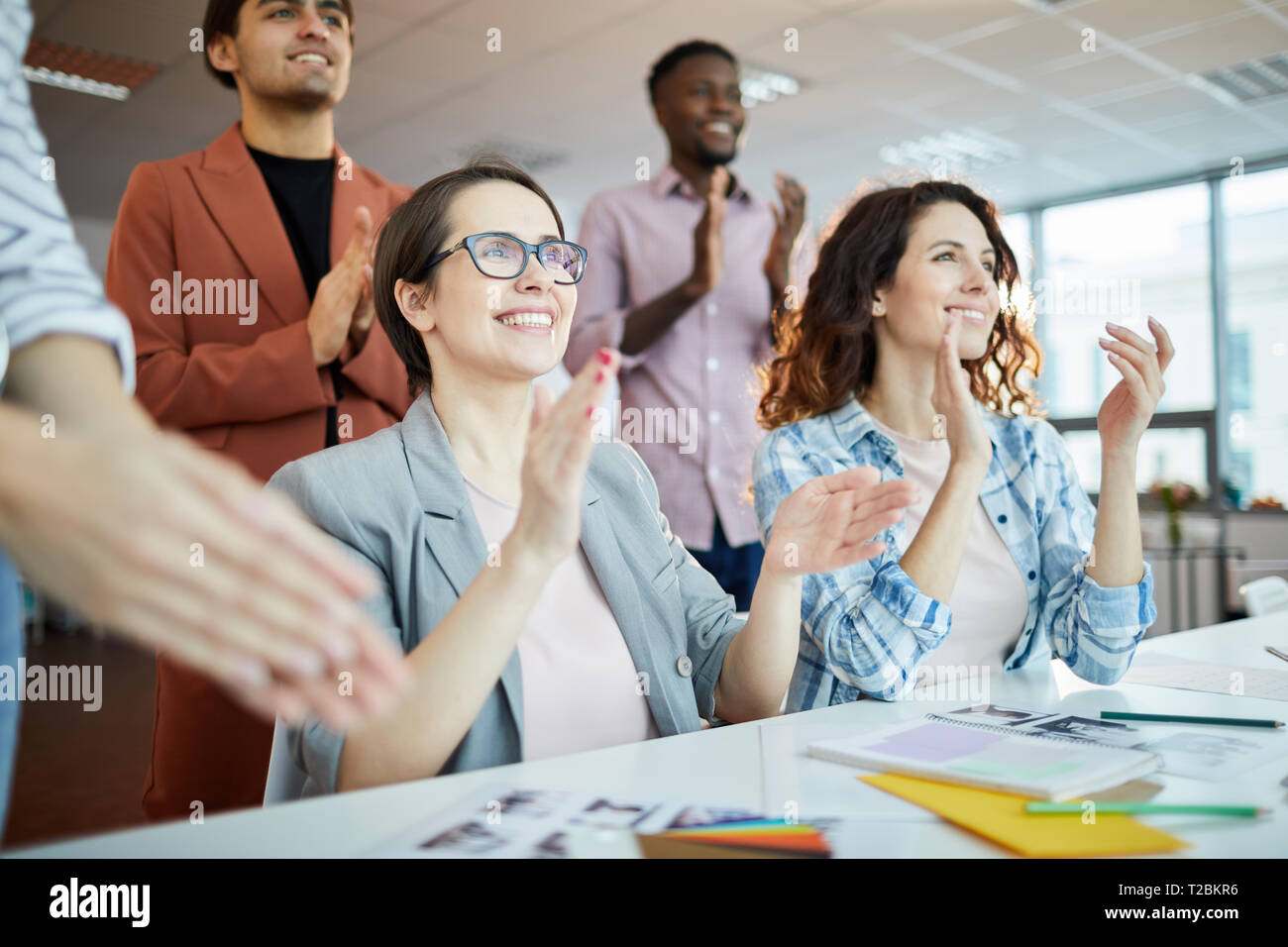 Portrait of multi-ethnic business team clapping during presentation in ...