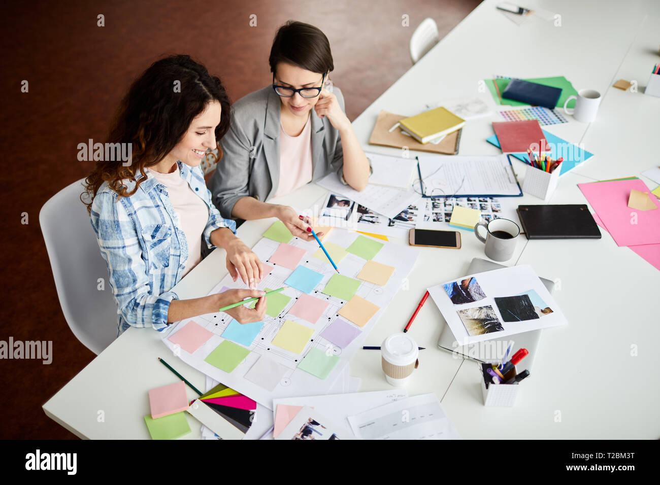 High angle portrait of two contemporary women planning project placing ...