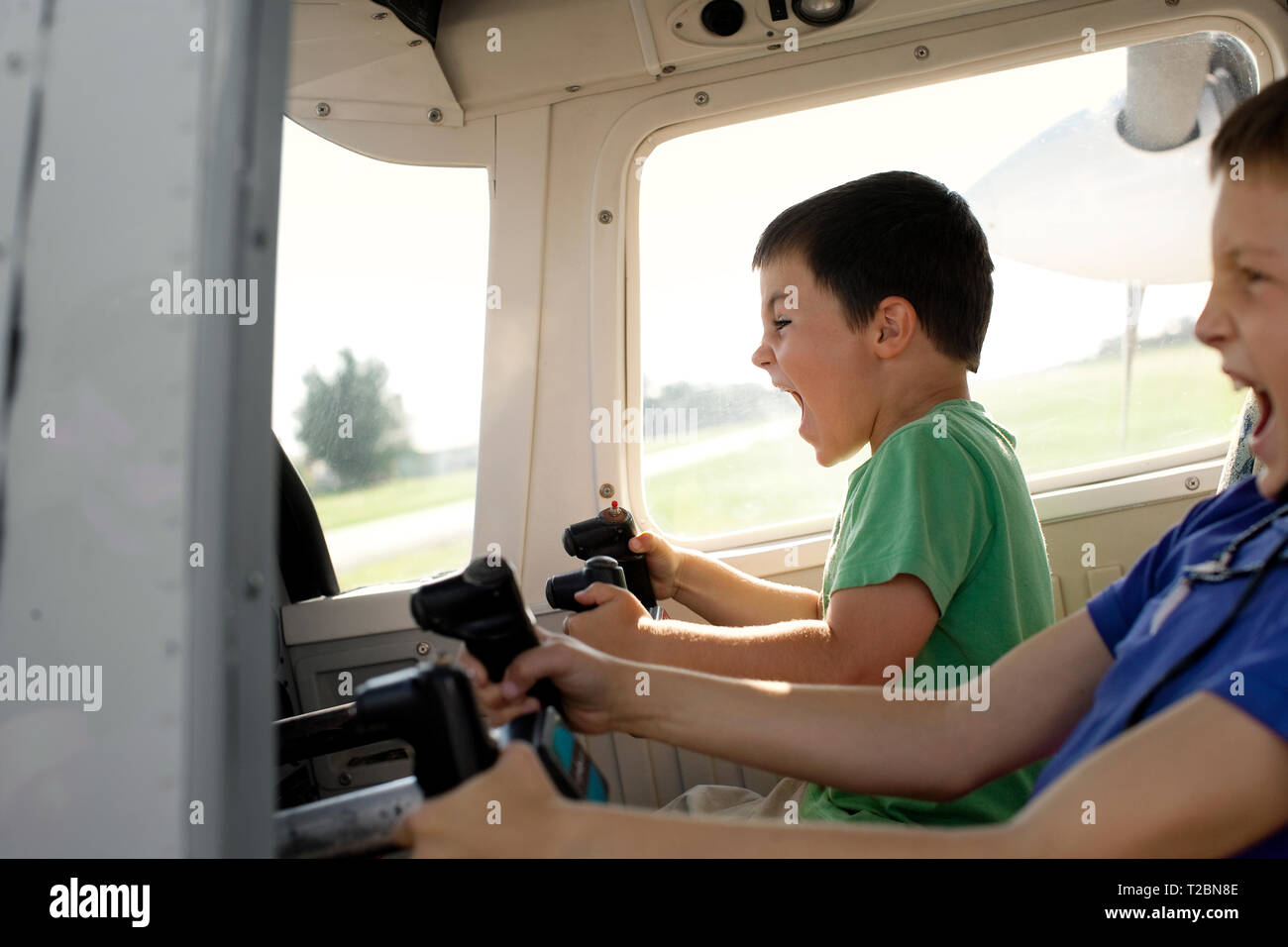 Two young boys pretending to fly a plane while sitting together inside ...
