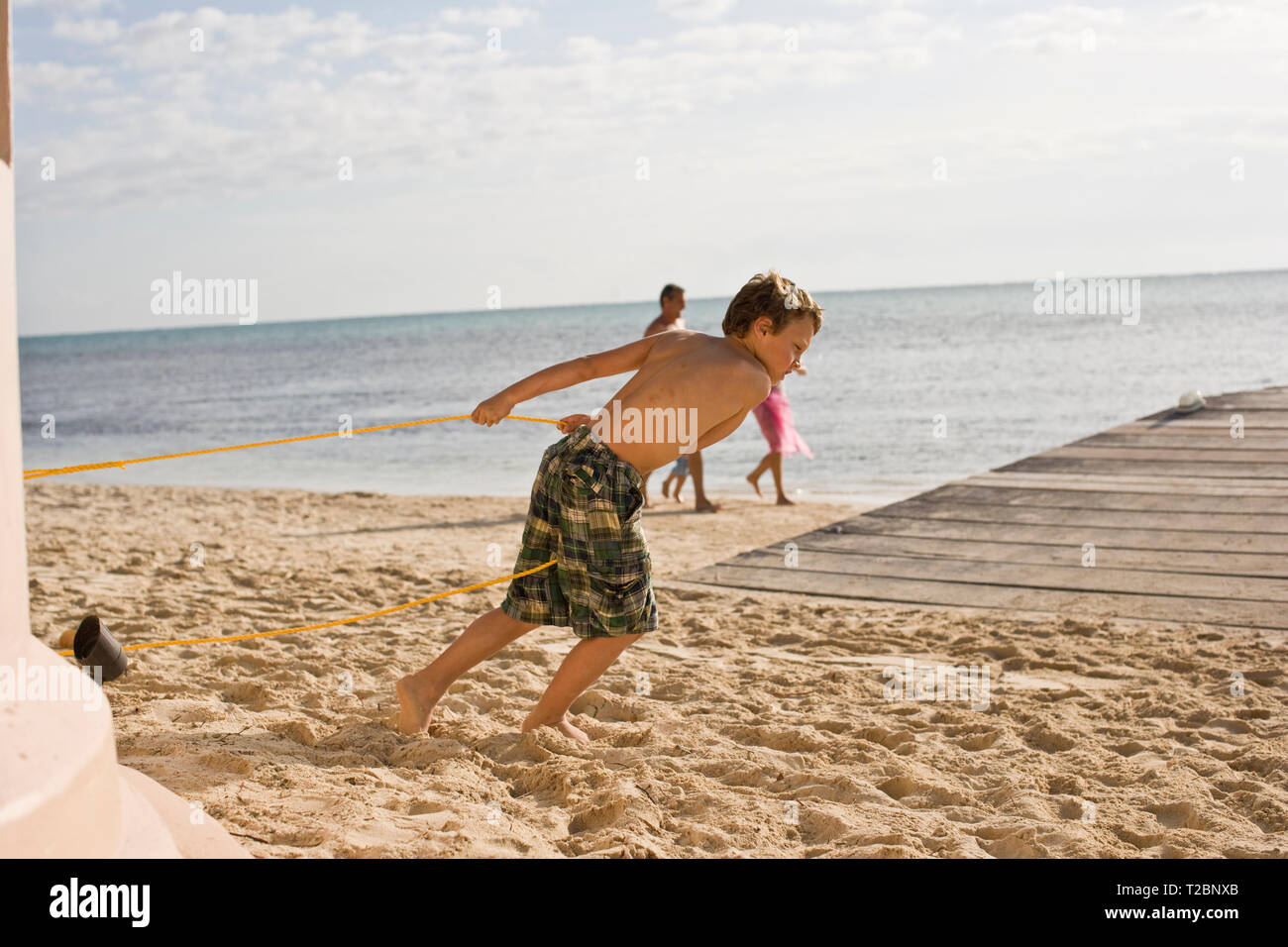 Boy dragging some rope along the beach Stock Photo - Alamy