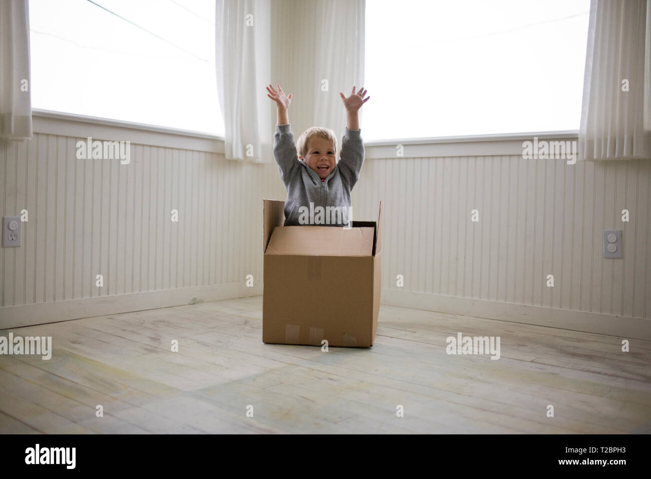 Boy jumping out of box in house Stock Photo - Alamy