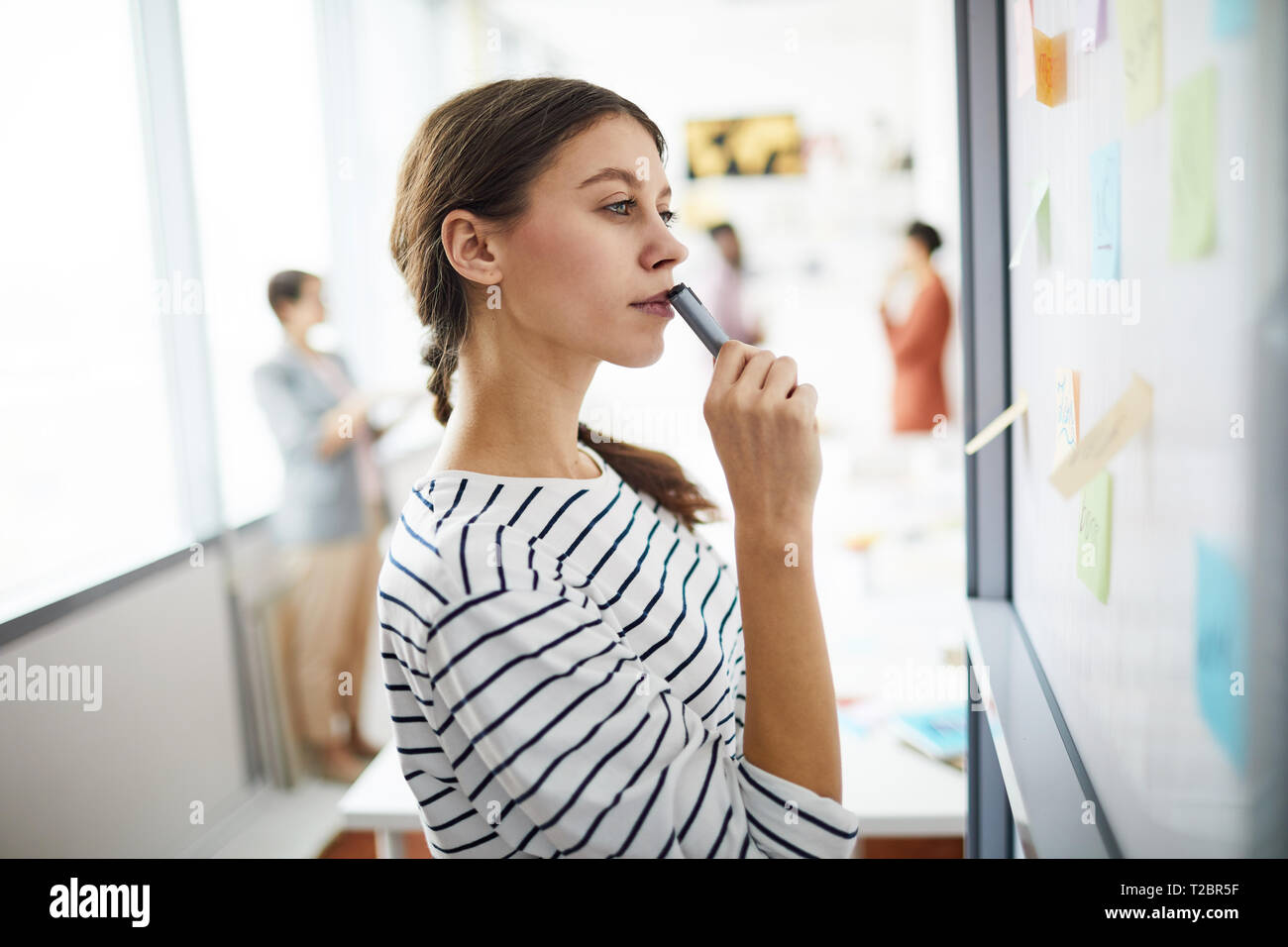 Side view portrait of contemporary young woman drawing on whiteboard in ...