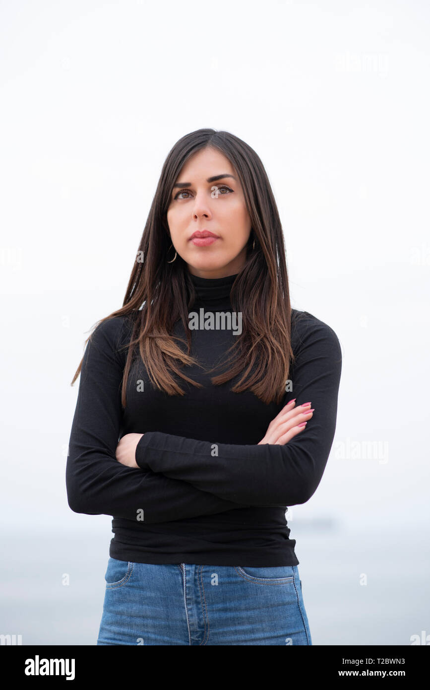 Beautiful woman arms folded looking away Stock Photo - Alamy