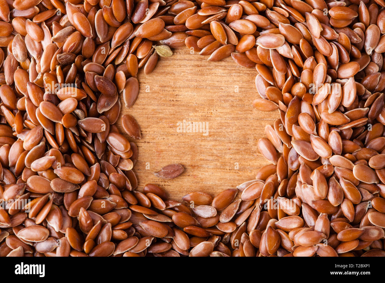 Healthy diet organic nutrition. Brown raw flax seeds linseed border frame on wooden table ...