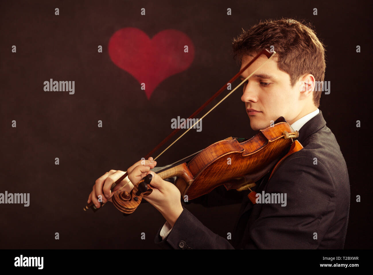 Art and artist. Young elegant in love man violinist fiddler playing violin on black background ...