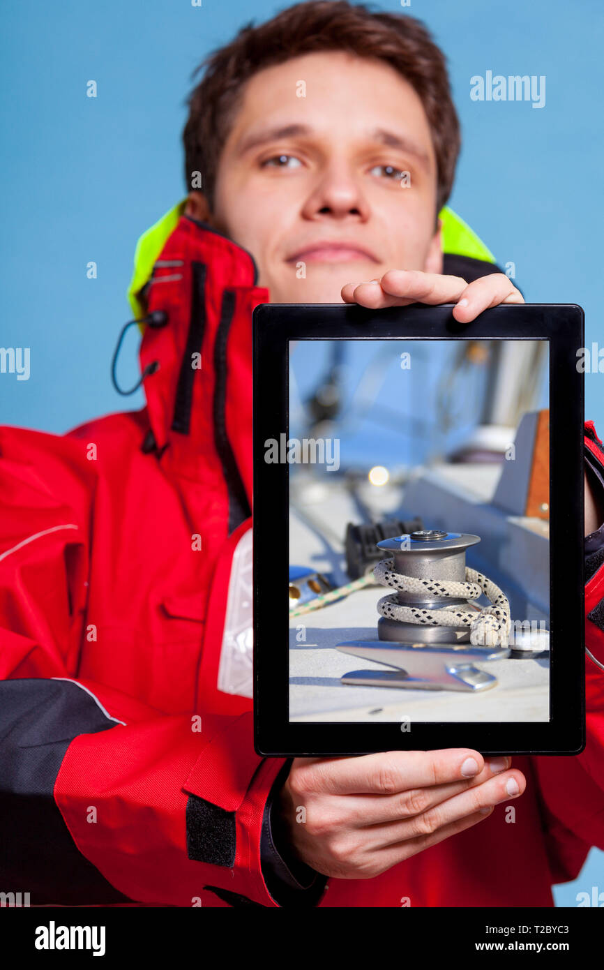 Man in wind jacket holding ipad with photo of yacht sailboat. Sailor ...